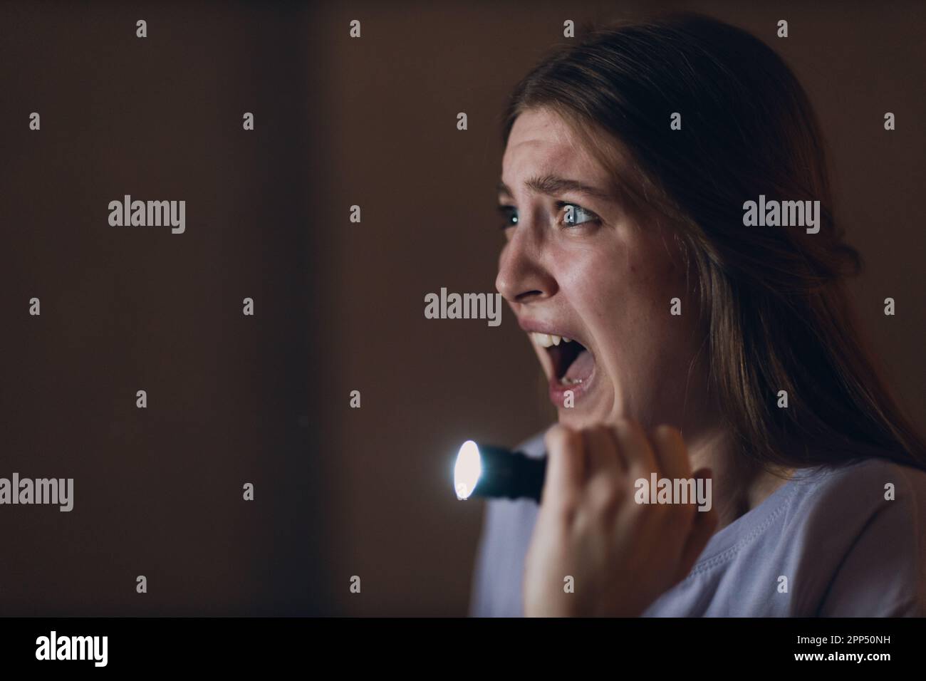 Woman scared holding hand flashlight in darkness and afraid of violence ...