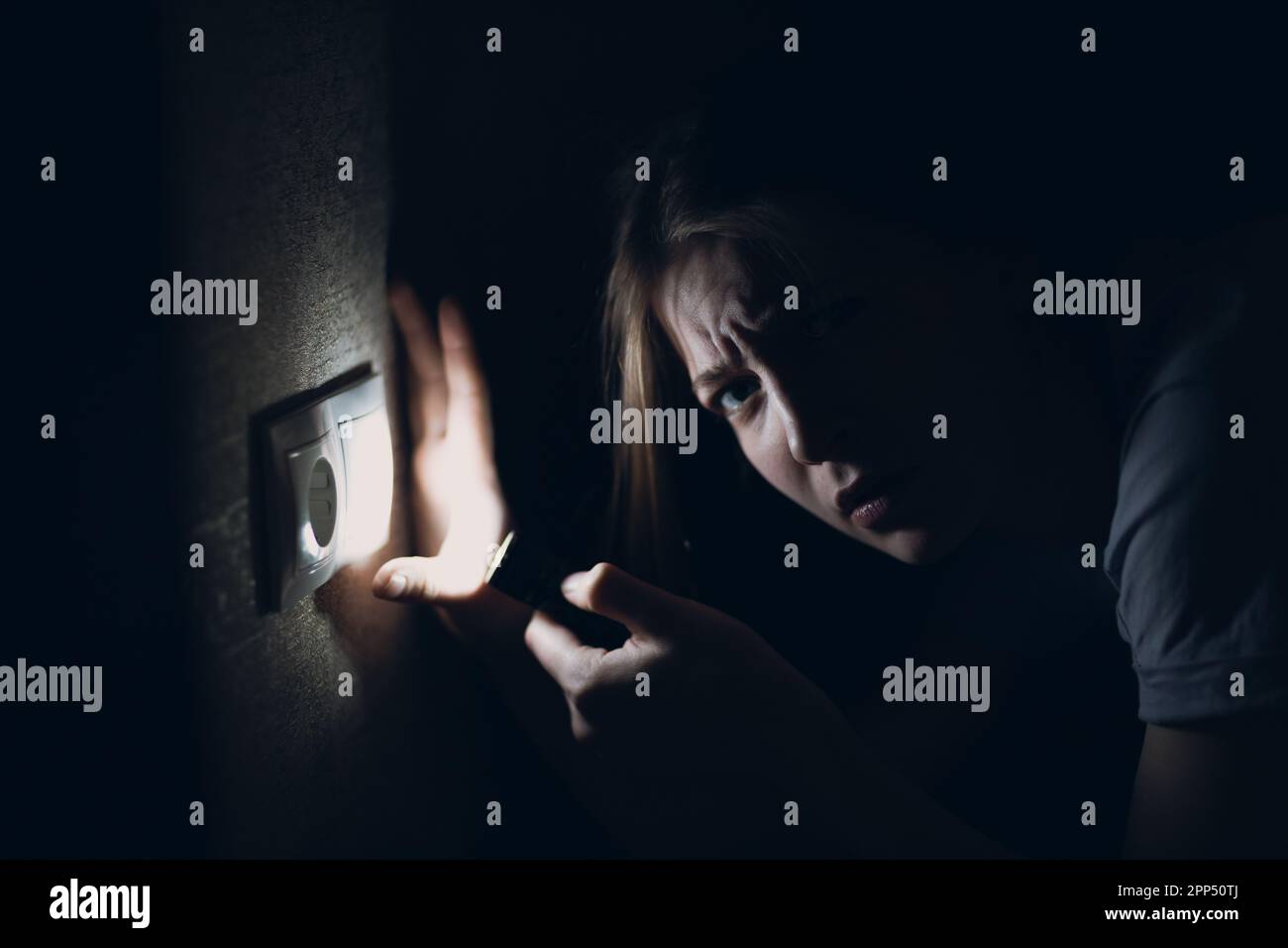 Woman young holding hand flashlight in darkness. Disconnecting home ...