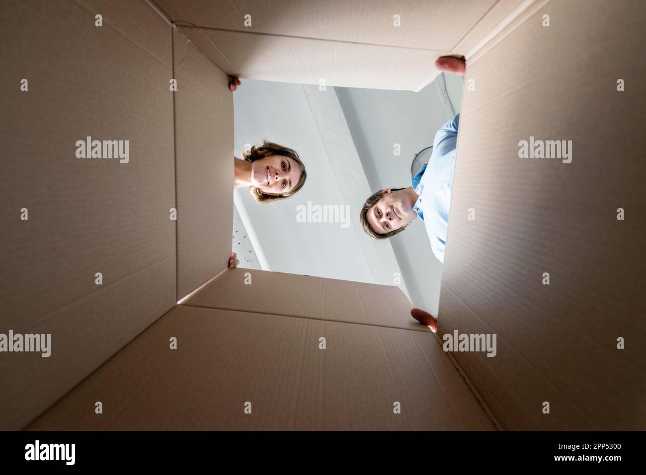 Couple looking inside empty box while packing move Stock Photo - Alamy