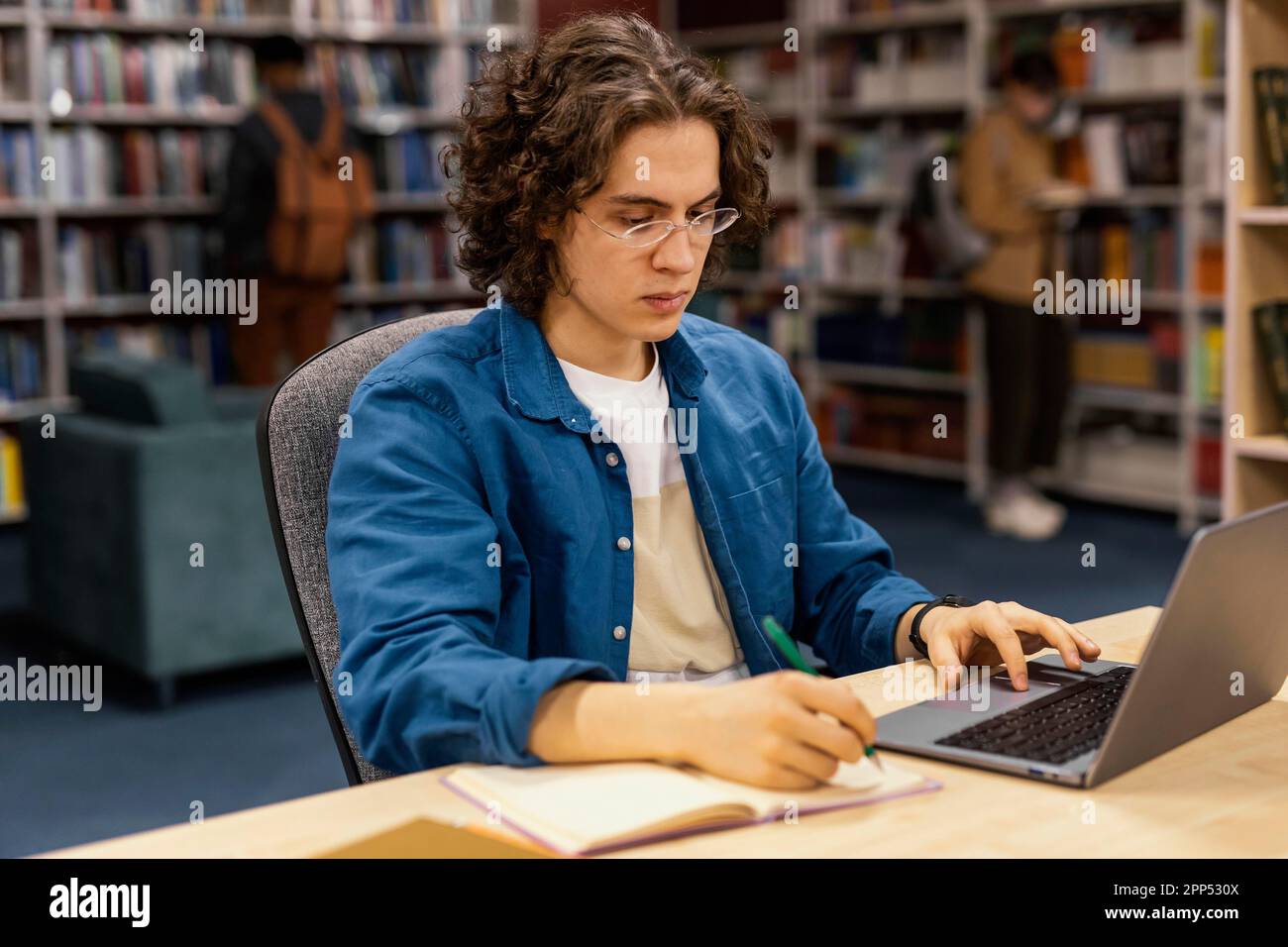 Boy studying university library Stock Photo - Alamy