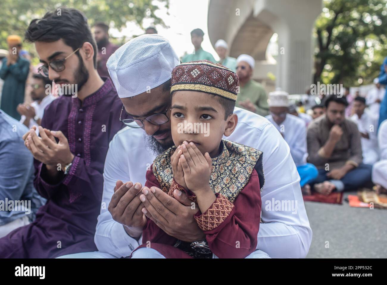 A Muslim man carrying a child offers Eid al-Fitr prayers marking the ...