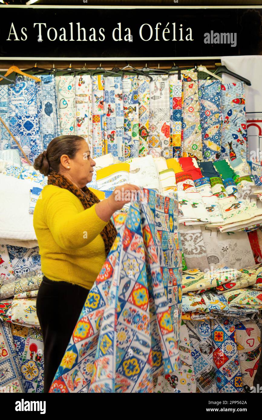 woman trader selling bolts of traditional cloth fabric in loule market ...