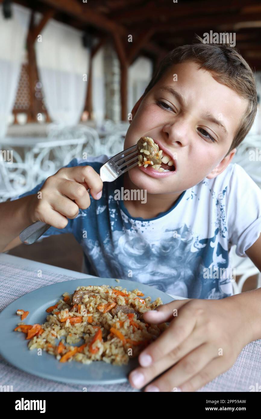 Hungry boy eating pilaf in a restaurant Stock Photo - Alamy