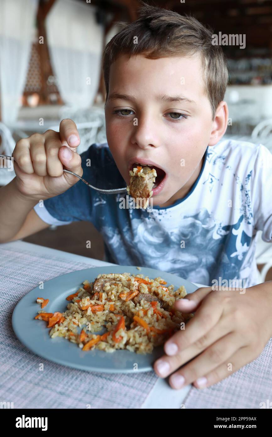 Hungry child eating pilaf in a restaurant Stock Photo - Alamy