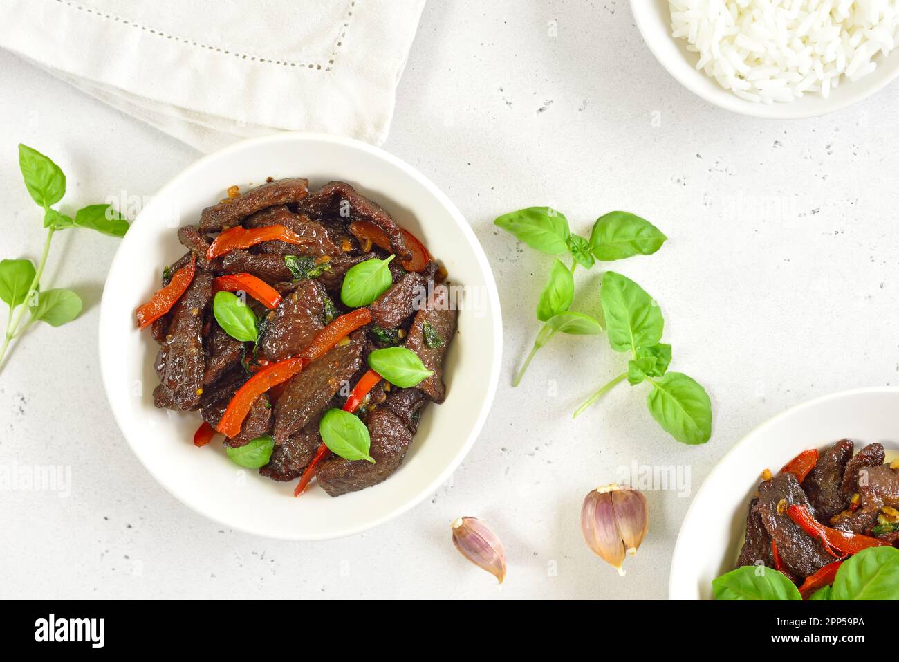 Thai beef stir-fry with pepper and basil in bowl over light stone ...