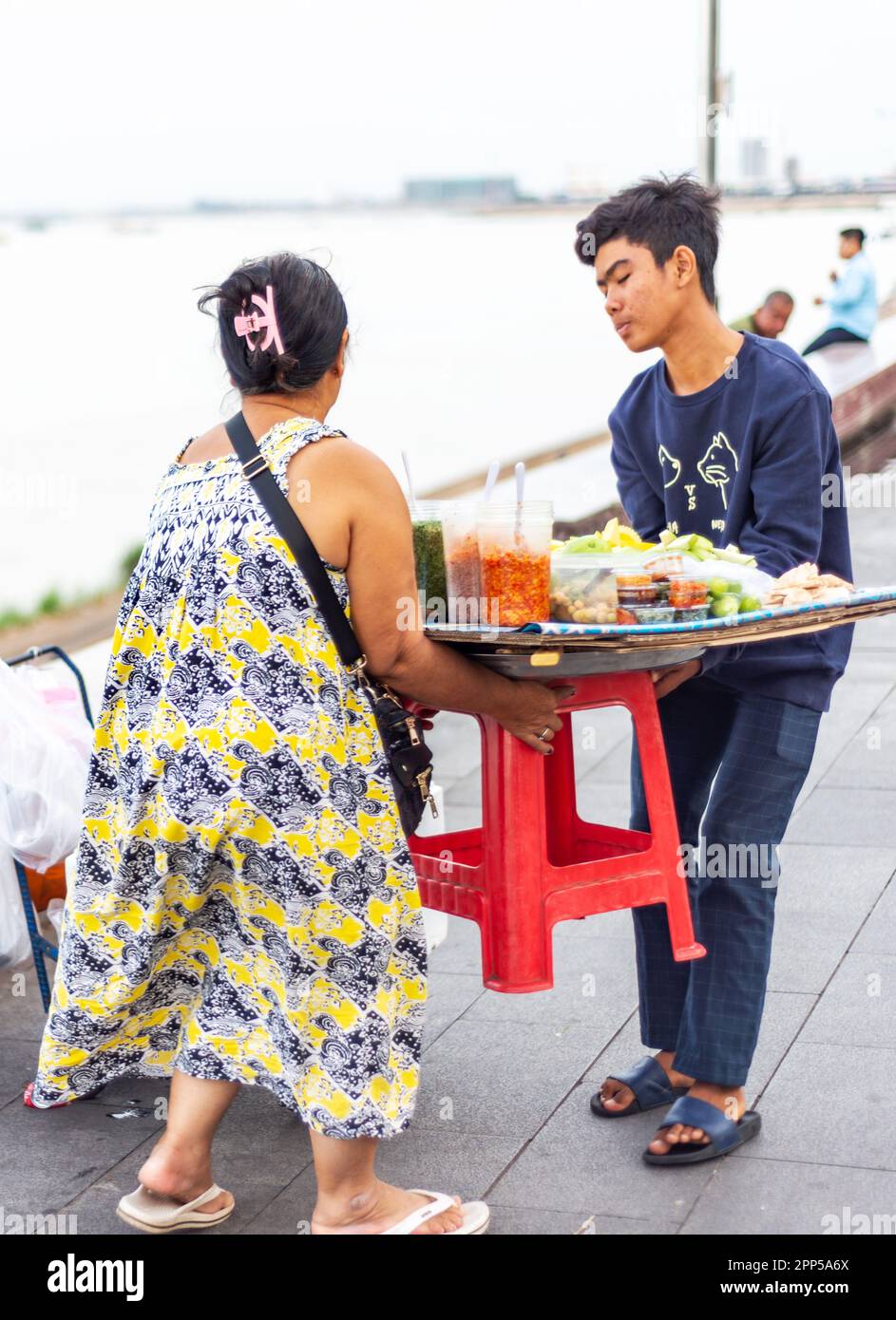Phnom Penh,Cambodia-January 4th 2023: A woman vendor gets assistance ...