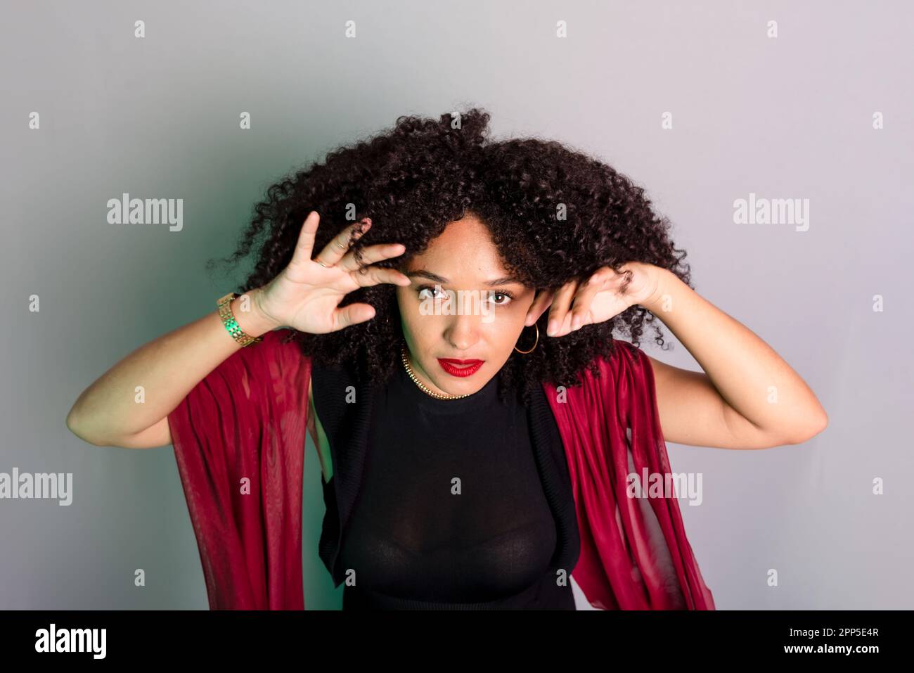 Beautiful young woman touching her hair with a red cloth. studio ...
