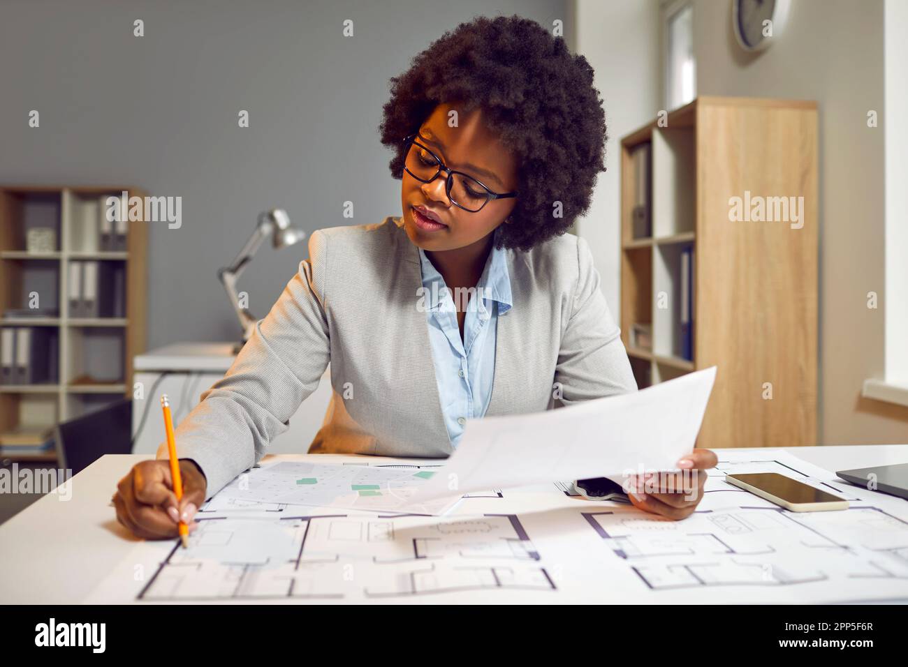 Female architect working on architecture project and drawing blueprint ...