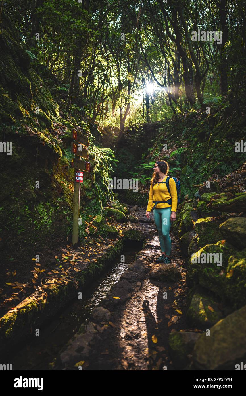 Description: Tourist woman reading a trail signage in front of a tunnel ...