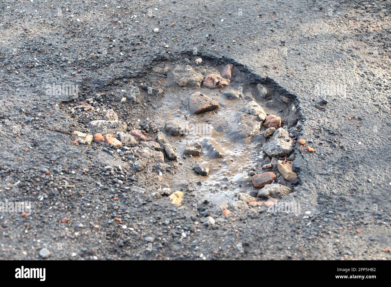 Pothole in asphalt road, danger for vehicles, bikes and pedestrians ...