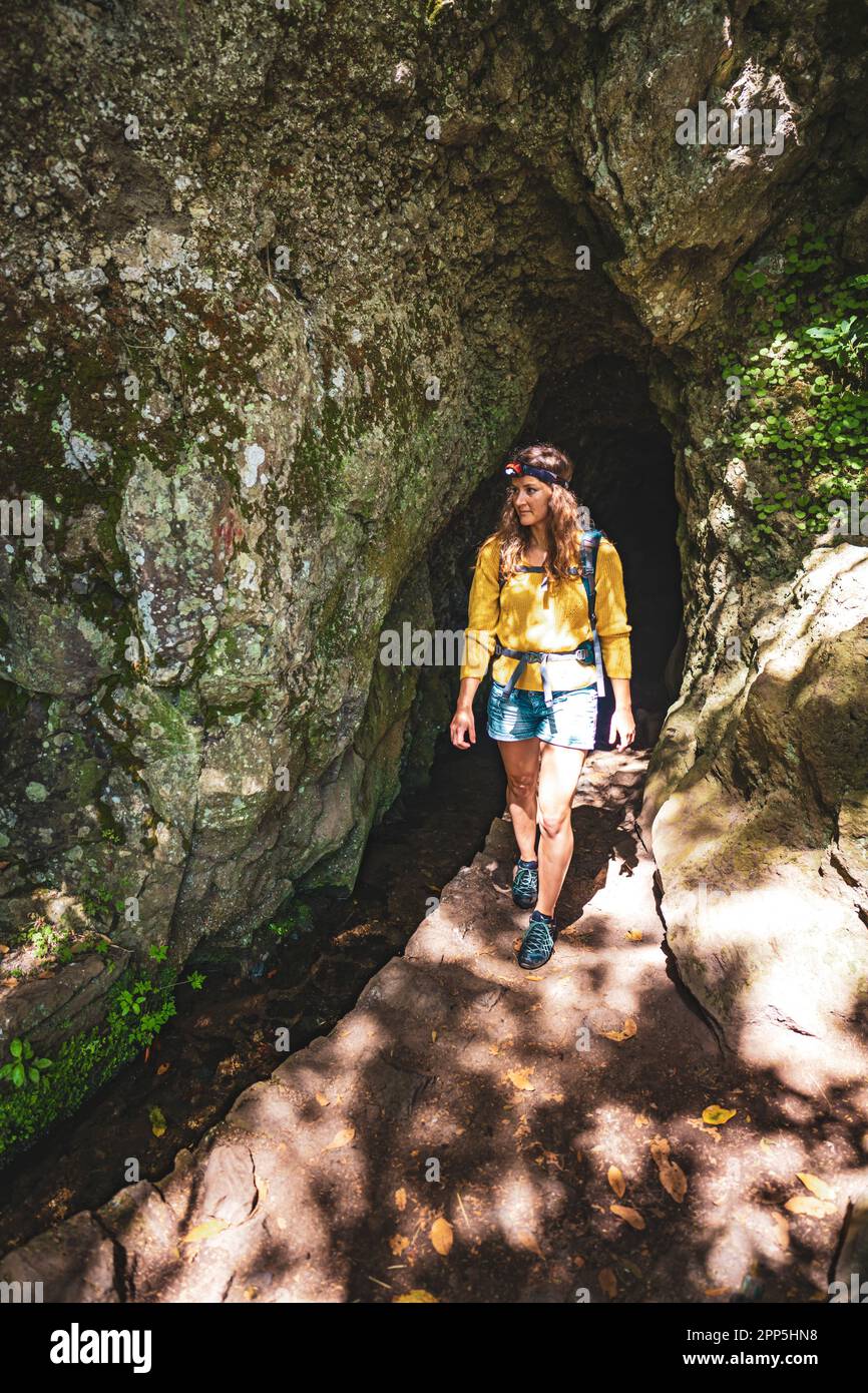 Description: Tourist woman exiting a tunnel along an overgrown jungle ...