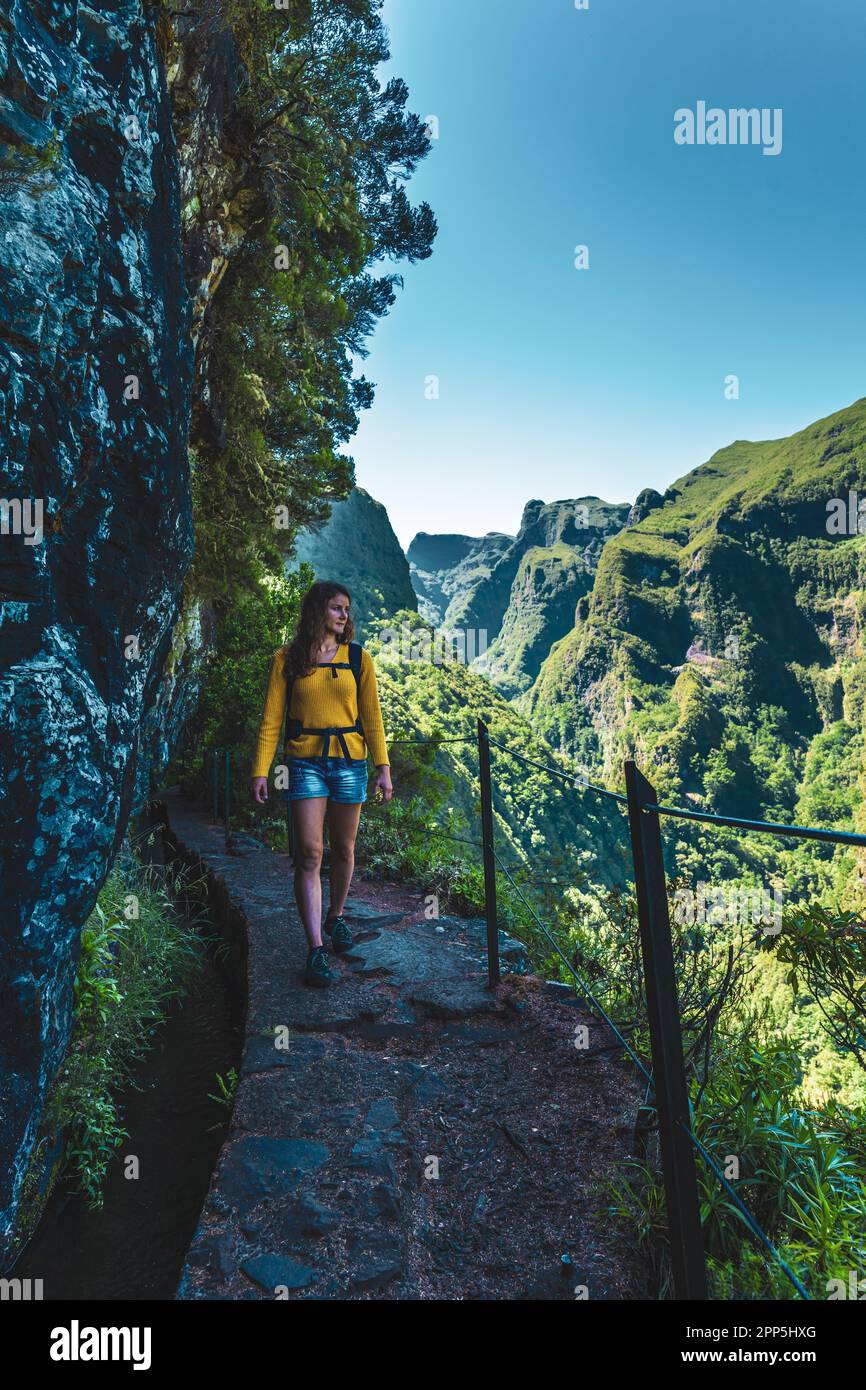 Description: Backpacker woman walking along steep cliff jungle hiking ...