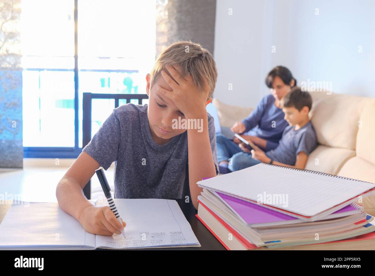 Children learning at home. Mother helping her son with homework and ...