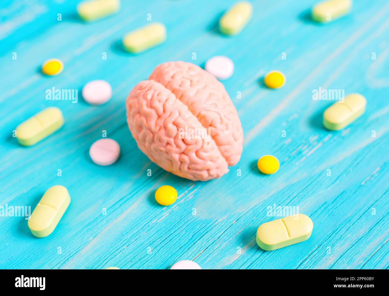 Miniature model of the human brain surrounded by scattered pills on a ...