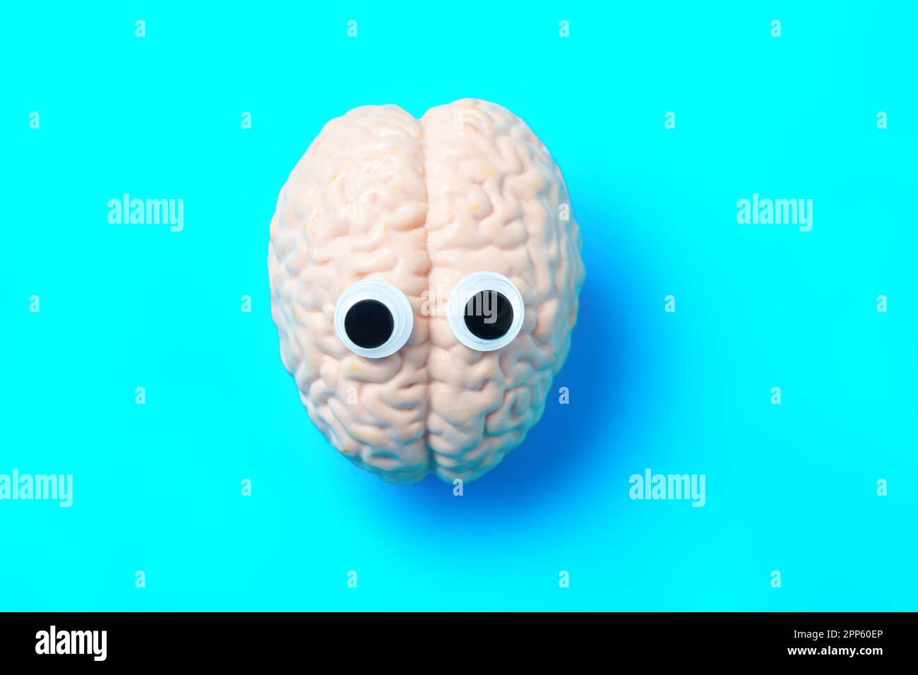Cartoonish human brain character with googly eyes against a blue ...
