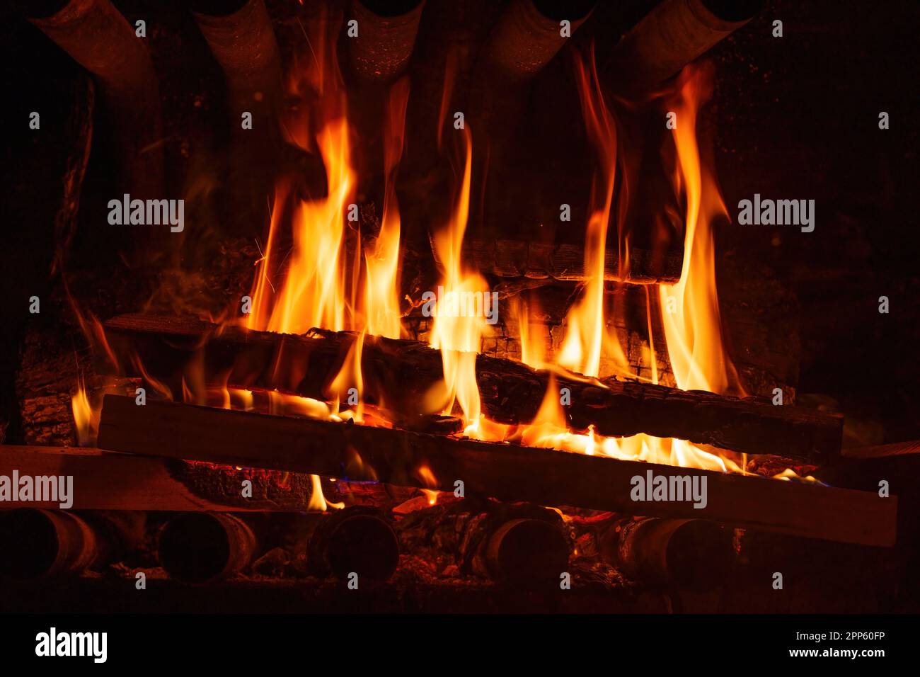 A close-up of a roaring fireplace, the burning wood emitting intense ...