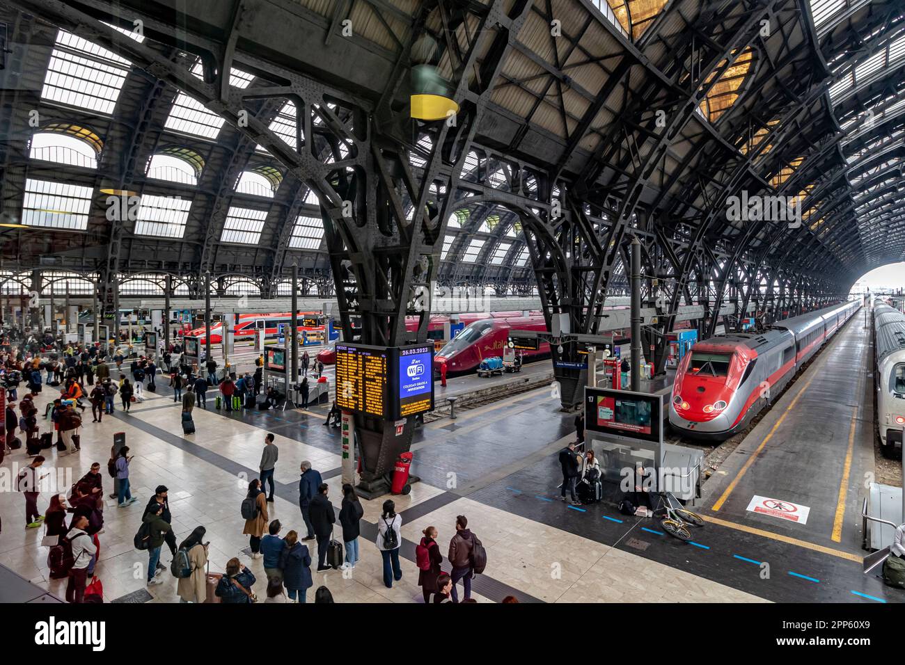Rail passengers walking through the main concourse of Milano Centrale railway station with it's ...