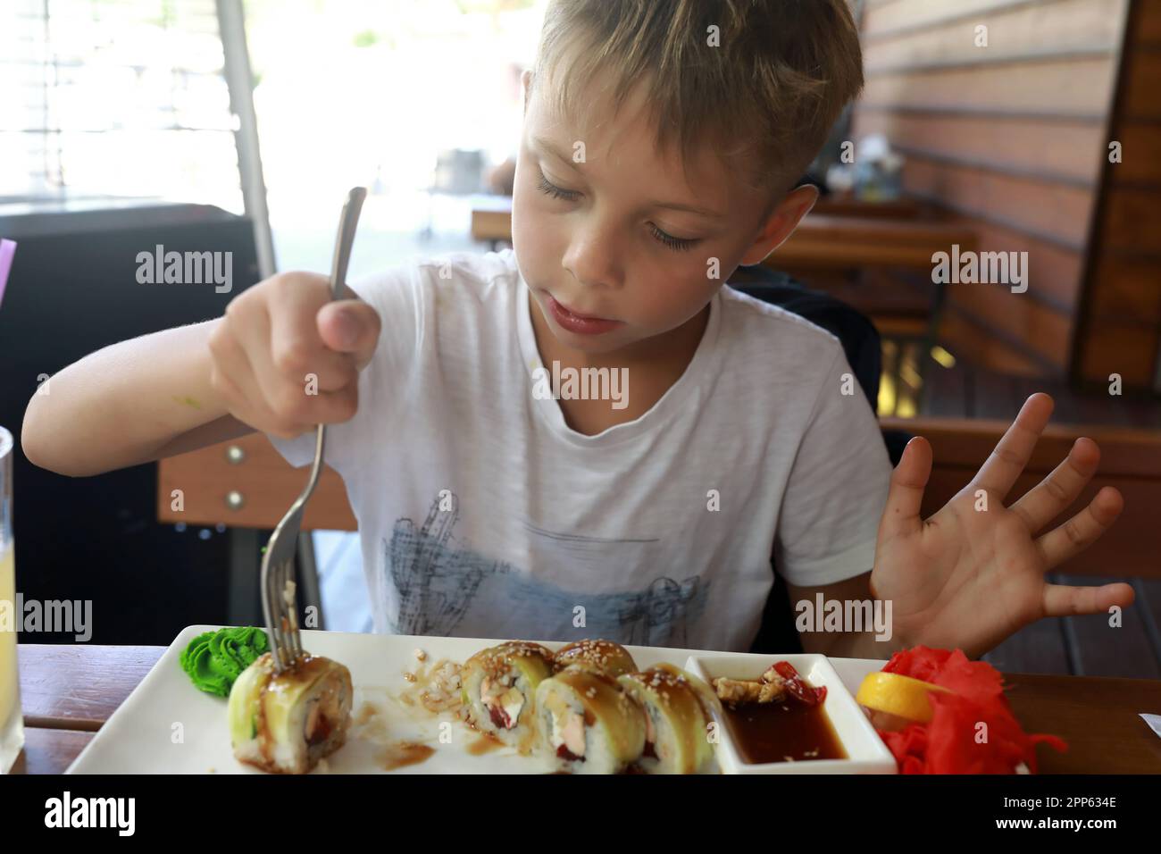 Boy eating sushi with fork in restaurant Stock Photo - Alamy