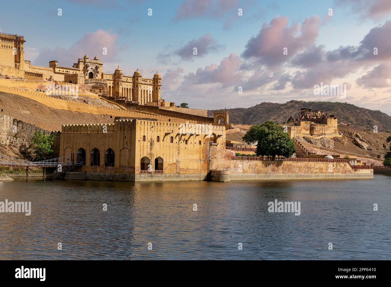 Amber Fort illuminated by warm light of the rising sun and reflected in ...