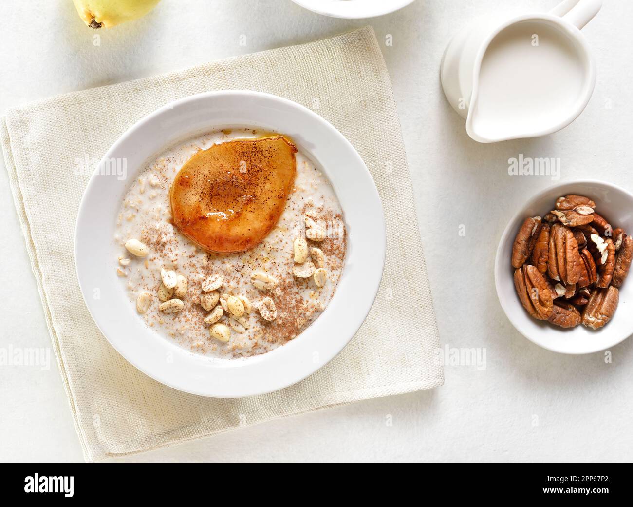 Oat porridge with caramelized pear and peanut in bowl over white ...