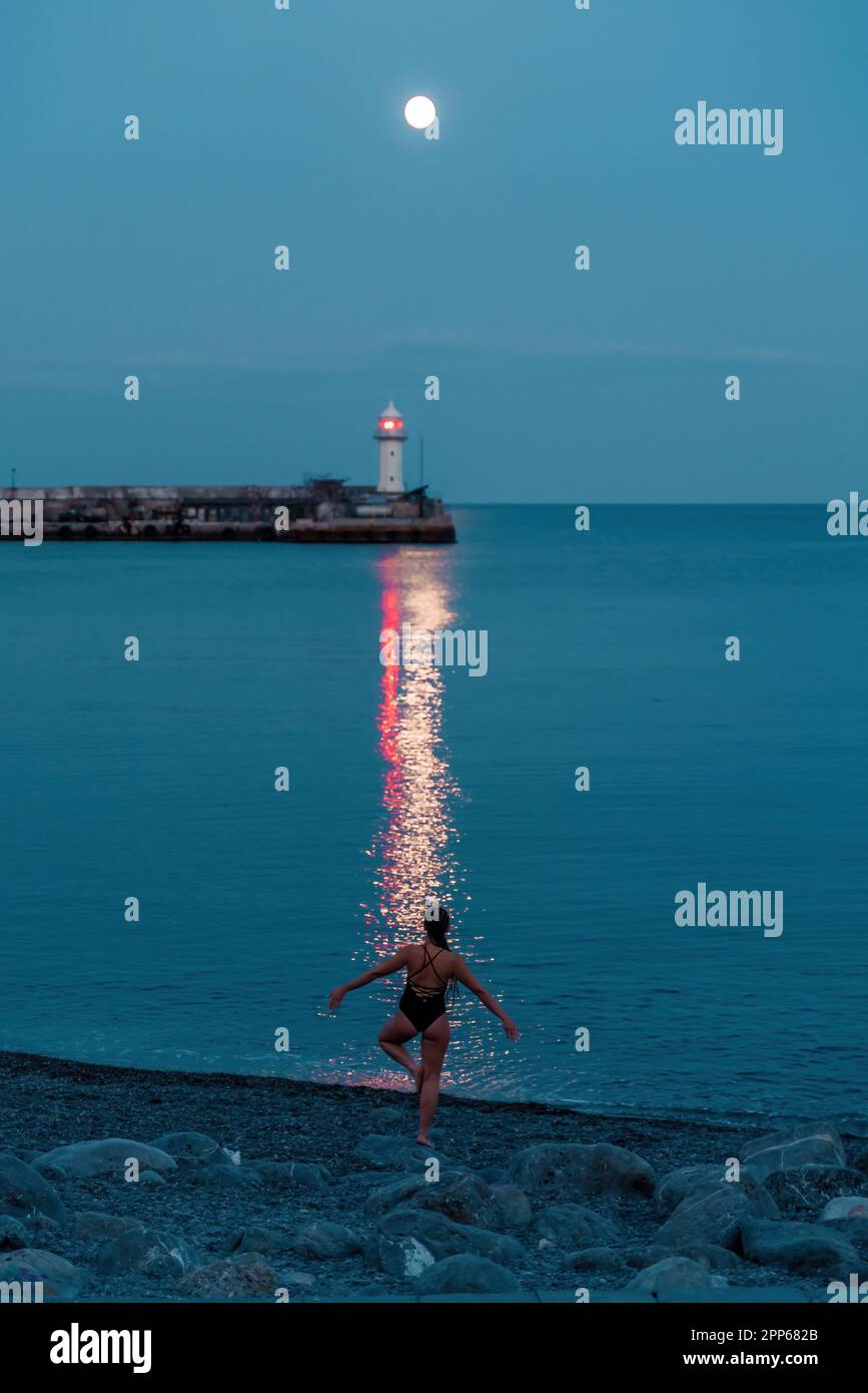 Woman The full moon rises to the lighthouse, the lunar path along the ...
