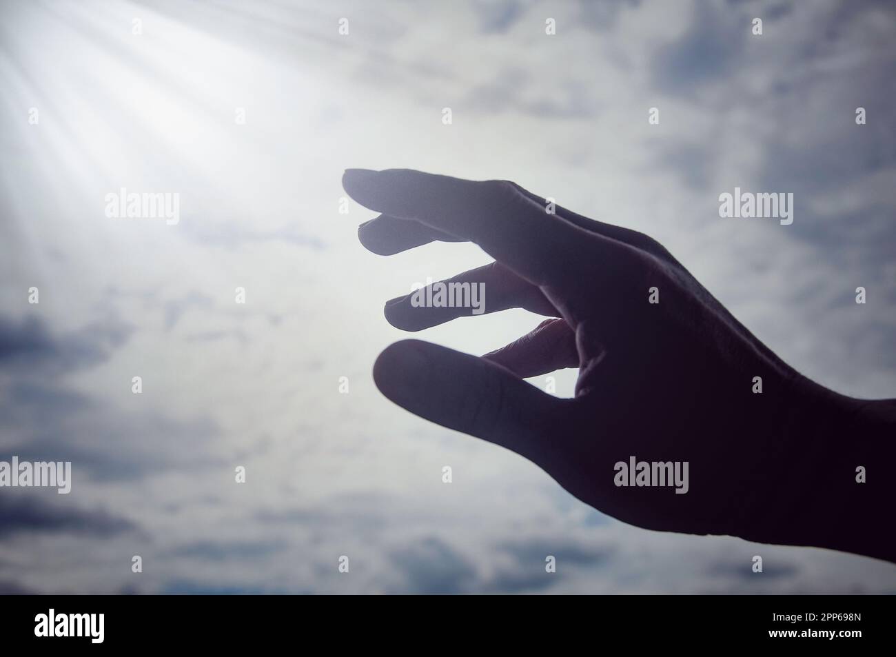 Hand reaching out to light shining from Heaven. Religious concept Stock ...