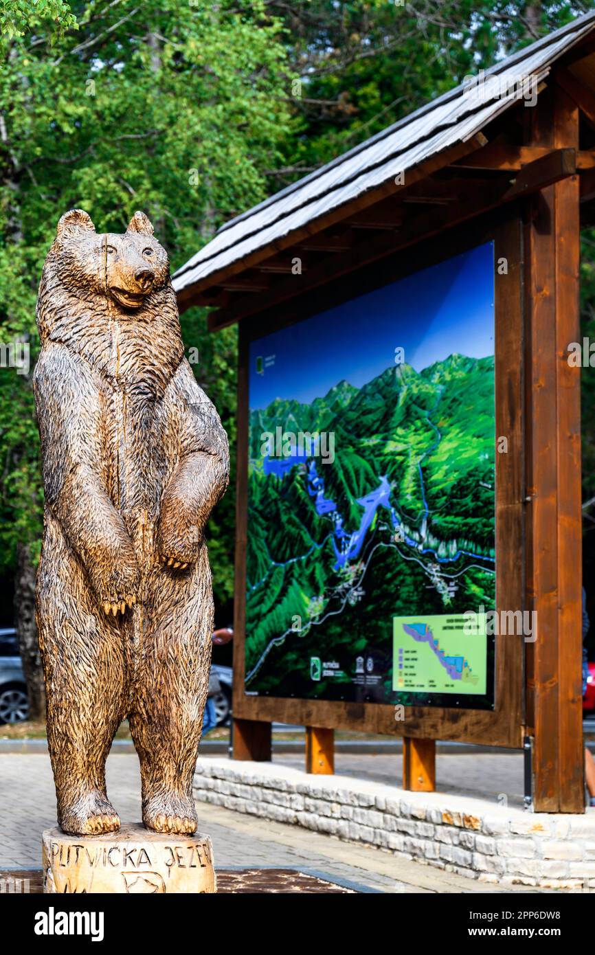A wooden bear statue in front of a traditional gazebo with a map ...