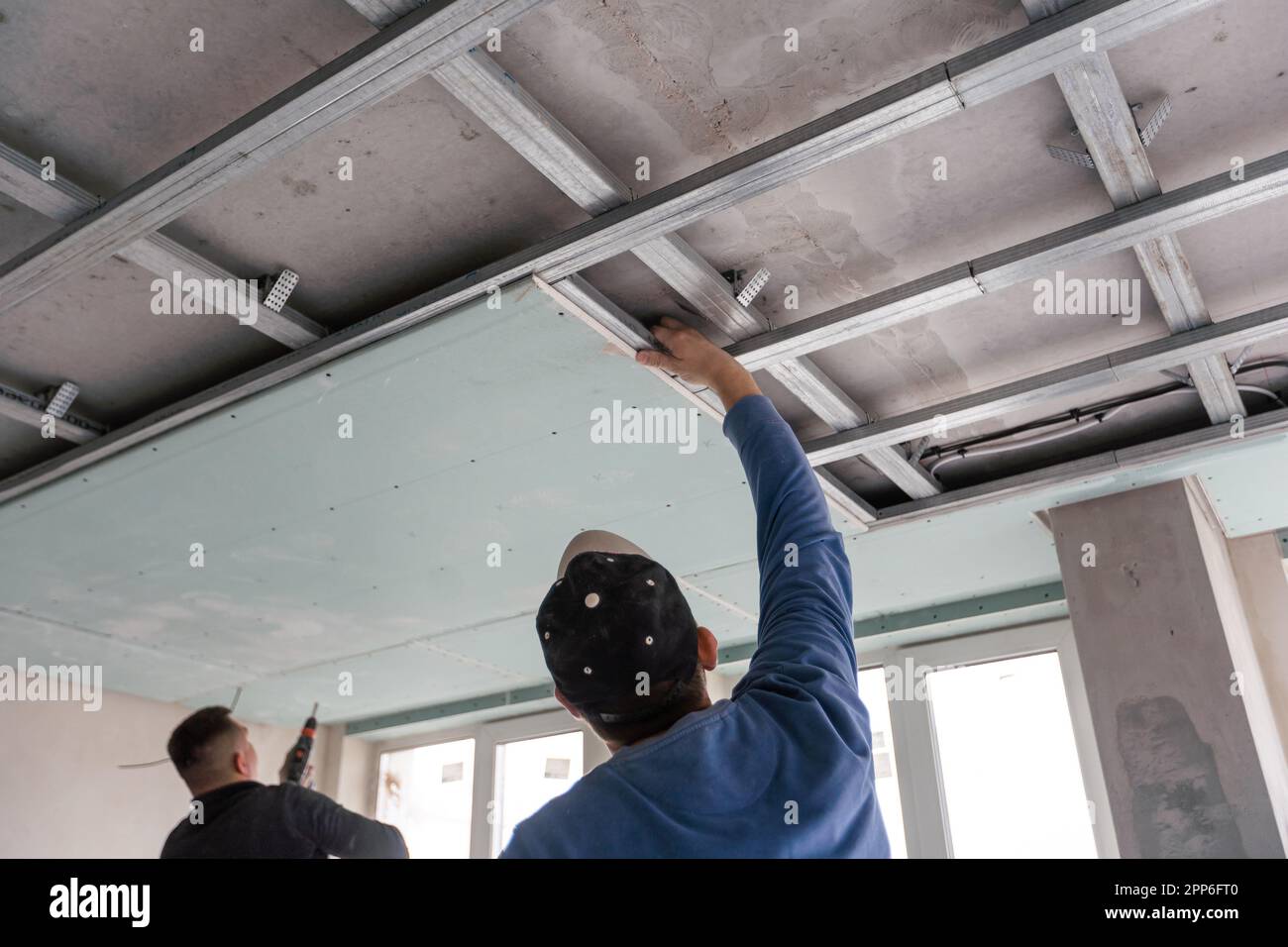 Workers fitting panel into frame of ceiling Stock Photo - Alamy