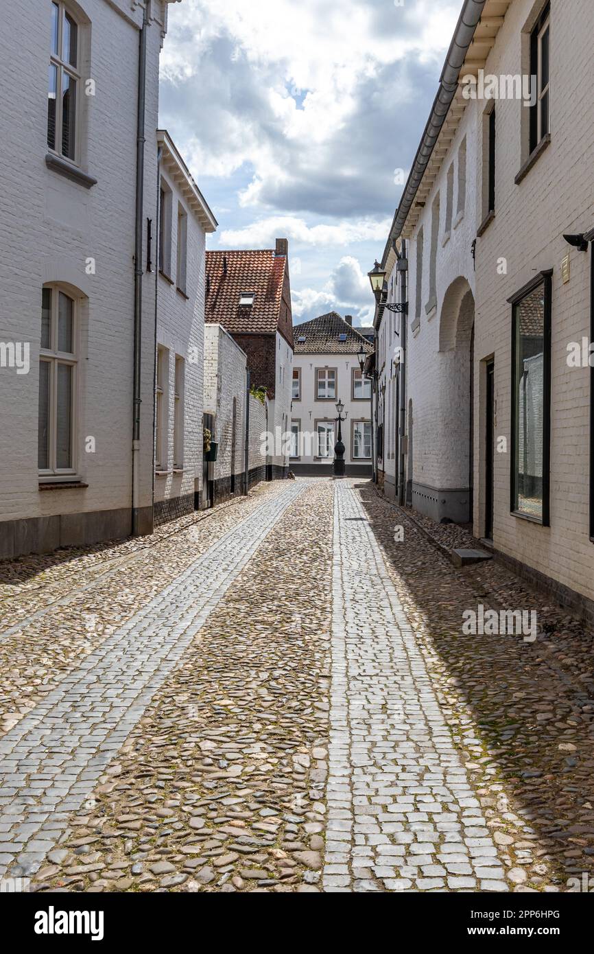 Landscape of narrow cobbled street between house with white walls ...