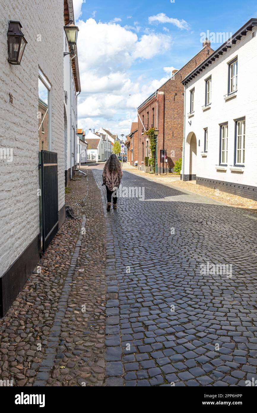 Cobbled street between houses with white and brick walls against blue ...