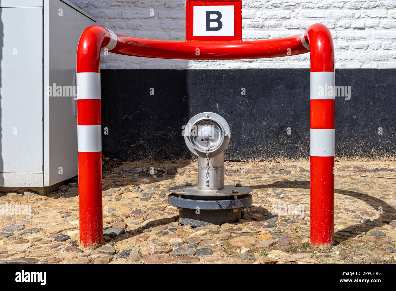 Fire hydrant between a red metal barrier with white lines against black ...