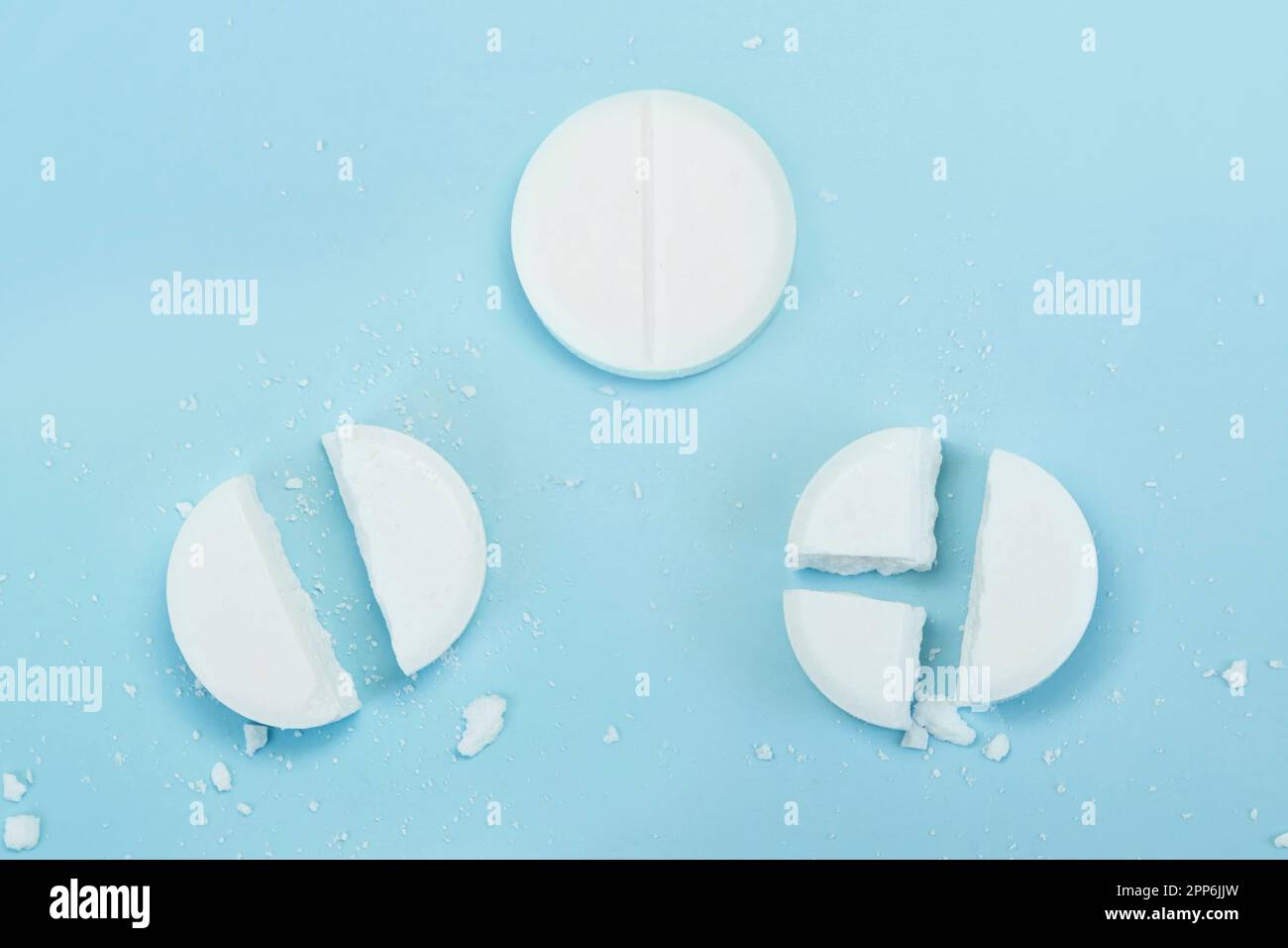 White pills on blue background. Few pills broken in half, reducing the ...