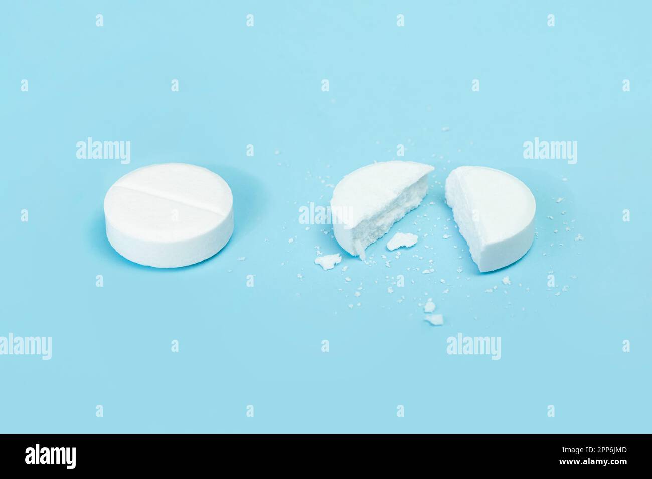 Two pills on a blue background, medicine,one tablet is broken in half ...