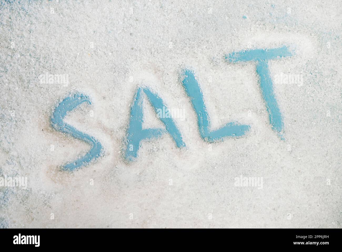 Salt grain top view on blue background. the word salt is written with ...