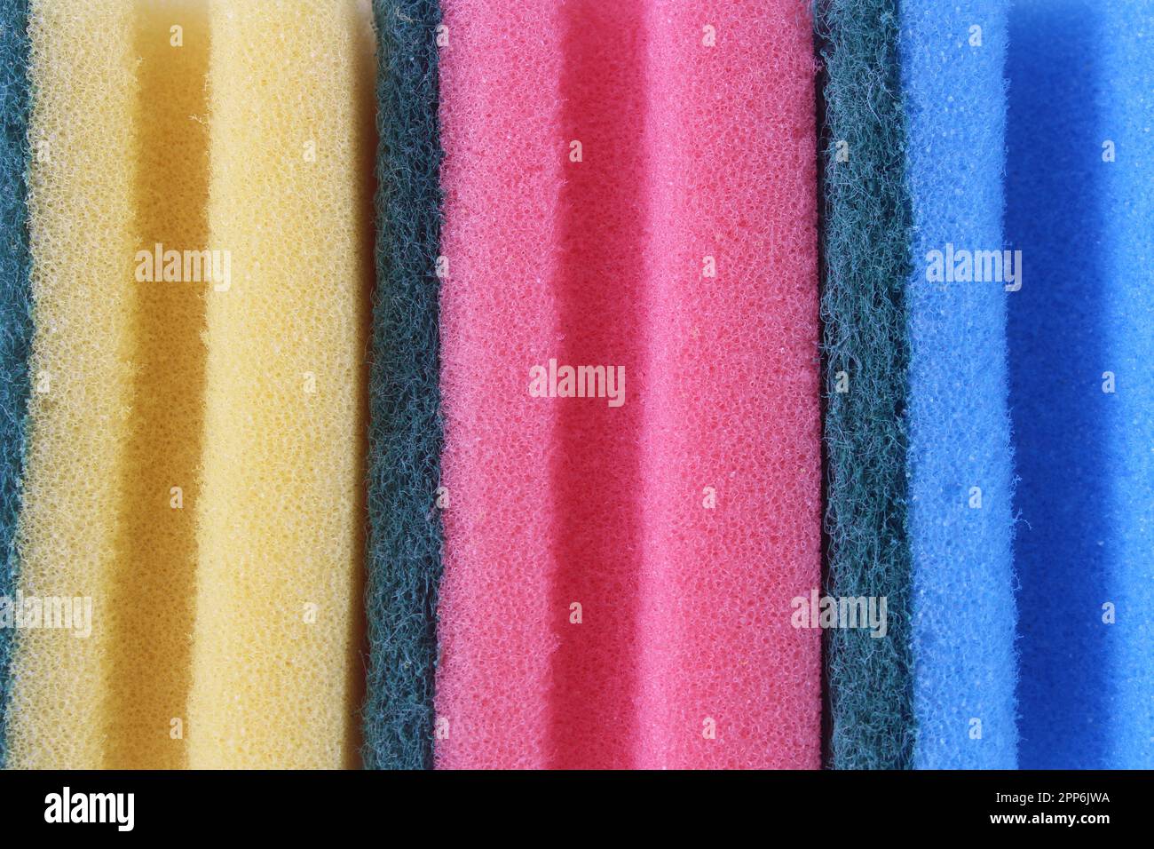 Close up on colorful sponge dish. Top view on pink, yellow and blue ...