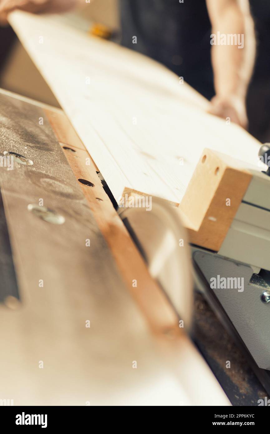 Strong carpenter's hands hold, guide, restrain, push, and move lumber ...