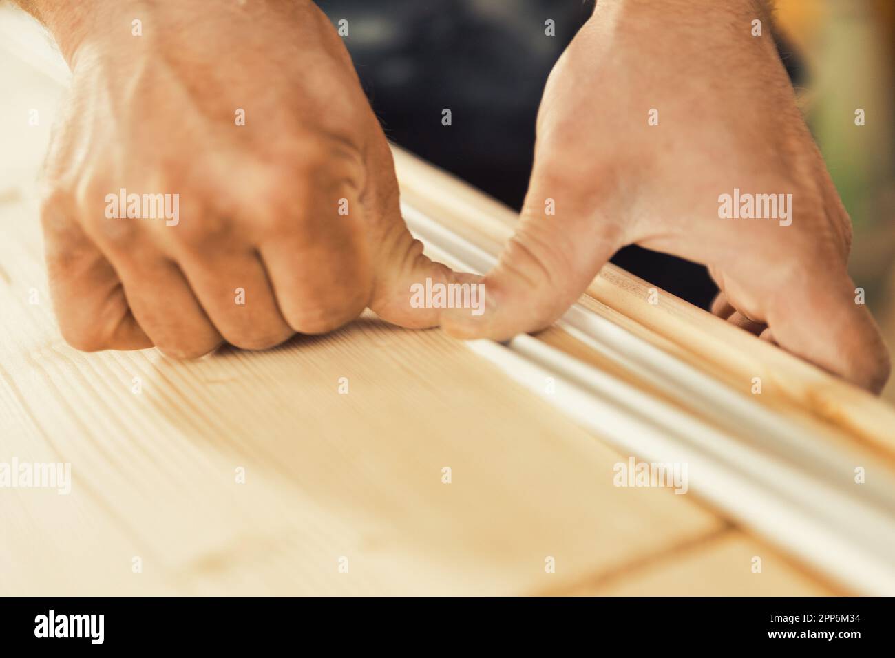 In sharp focus, the woodworker's hands carefully position, insert, and ...