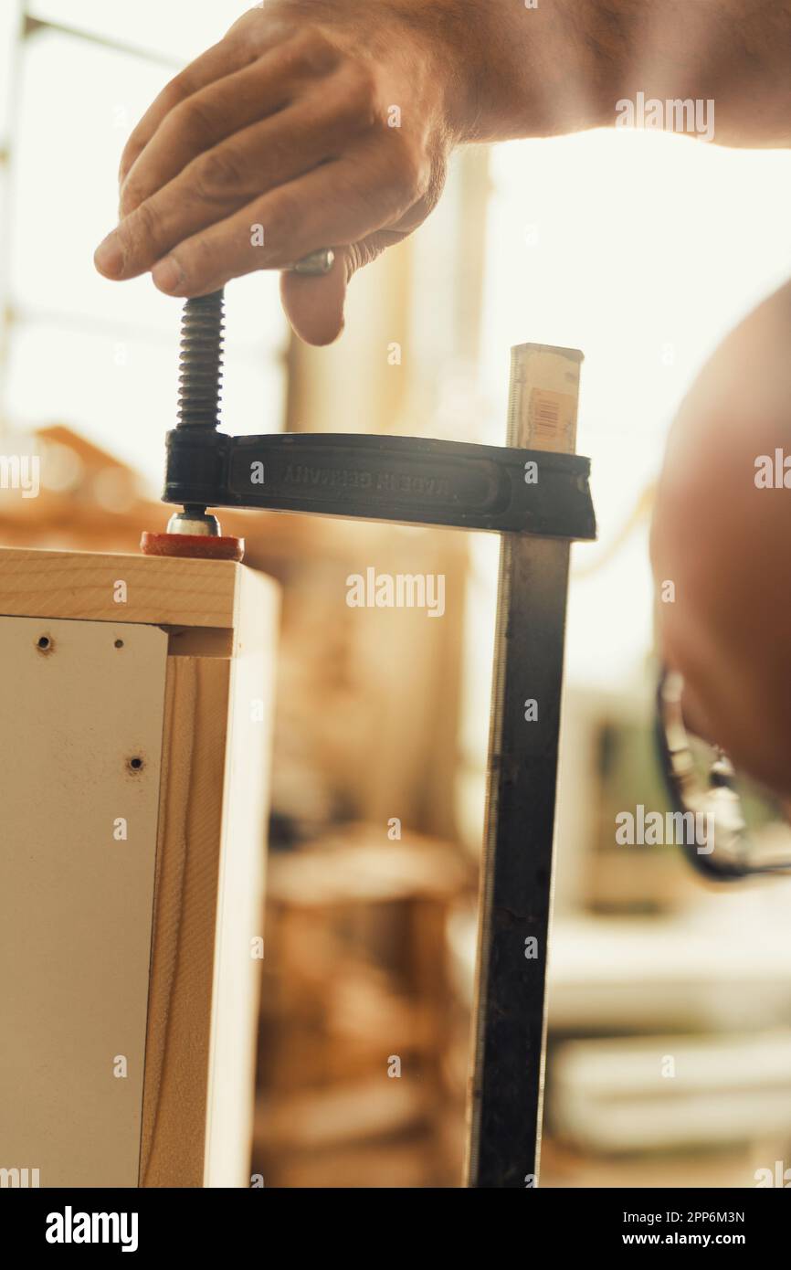 Wood artisan works traditionally in his shop. Carpenter tightens a ...