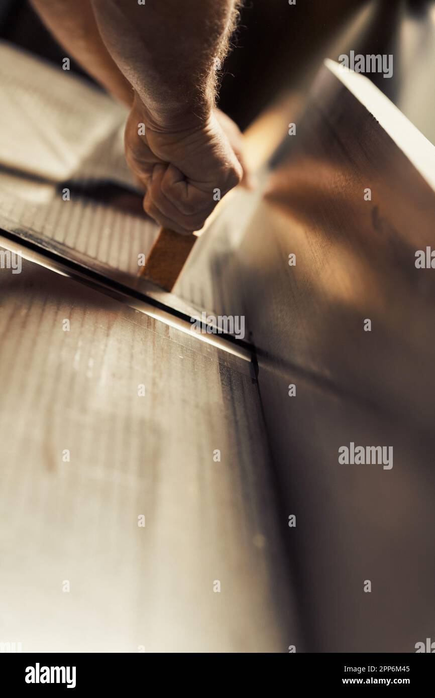 The strong and muscular hand and forearm of a carpenter holding a metal ...