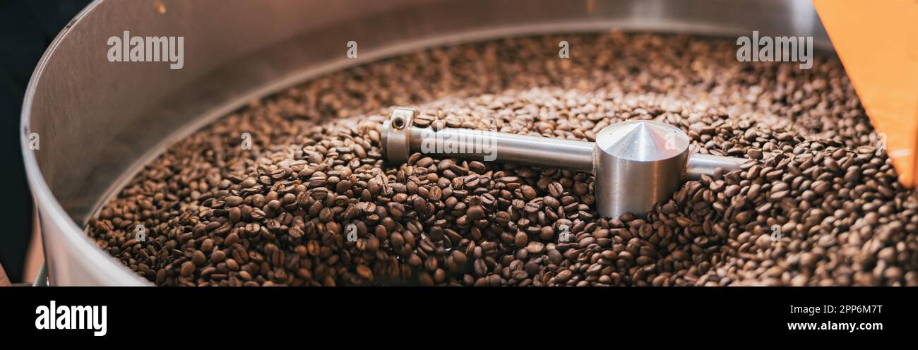 Close up of worker hands roasting coffee beans in roasting machine ...