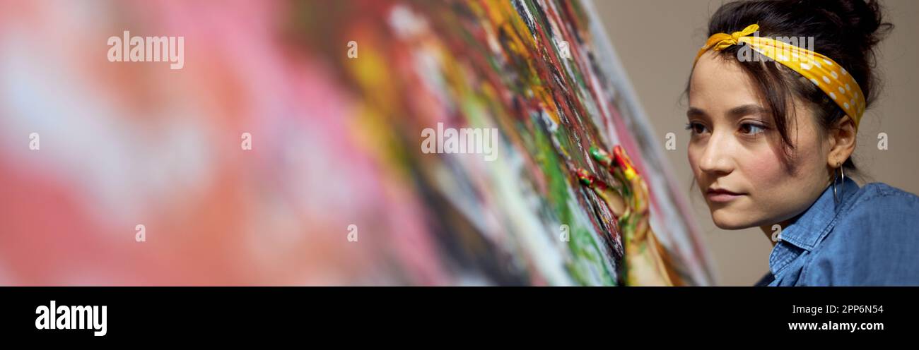 Portrait of young woman, female painter applying paint on canvas with ...