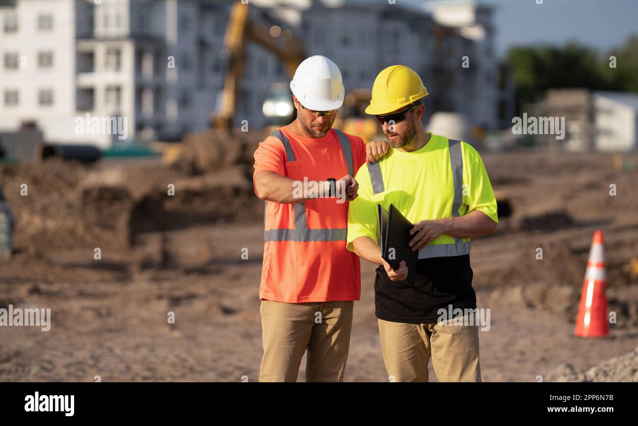 Construction foreman and civil engineer at work checking time schedule ...