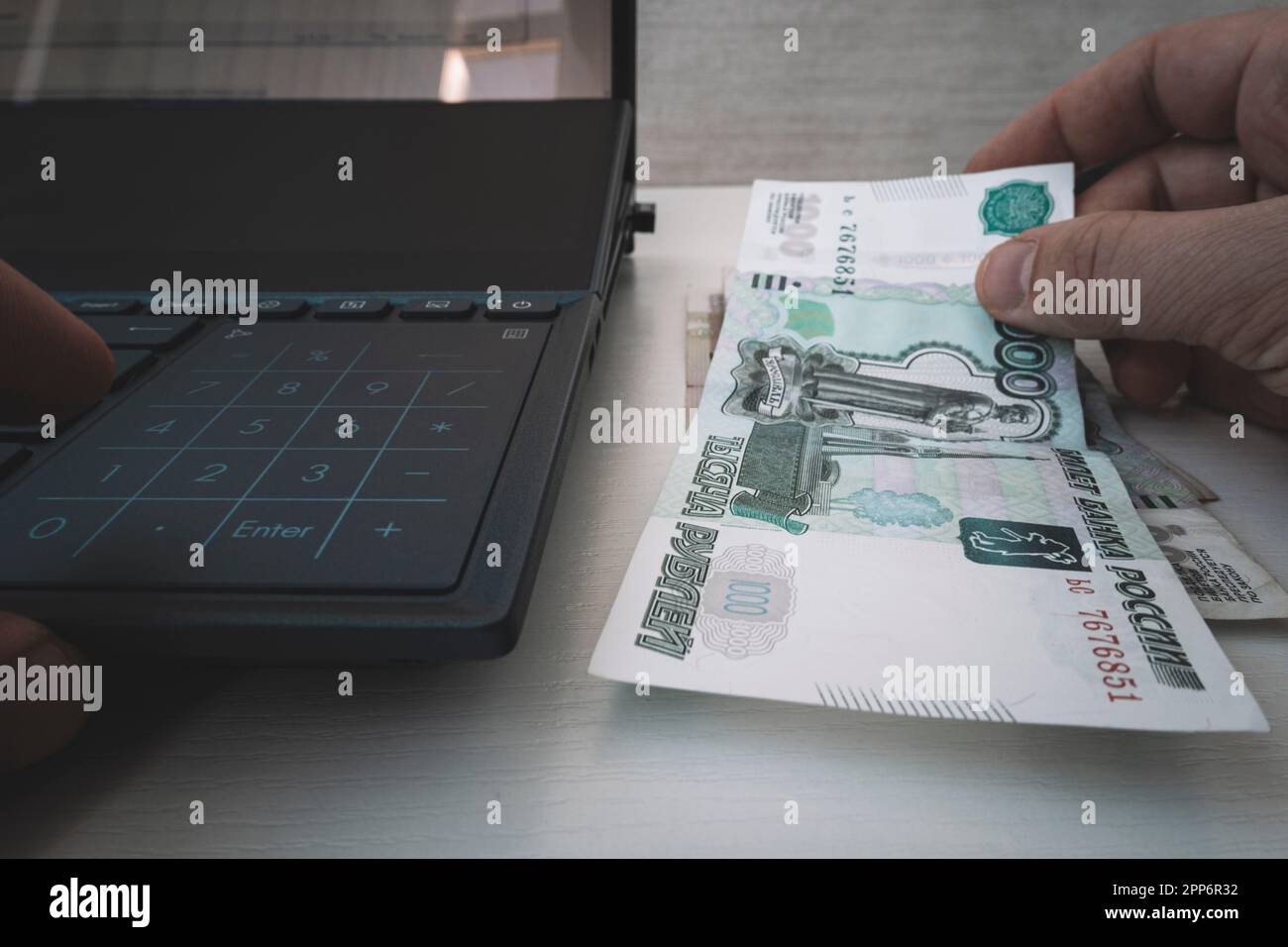 man presses a calculator button with his finger. man counting ruble ...