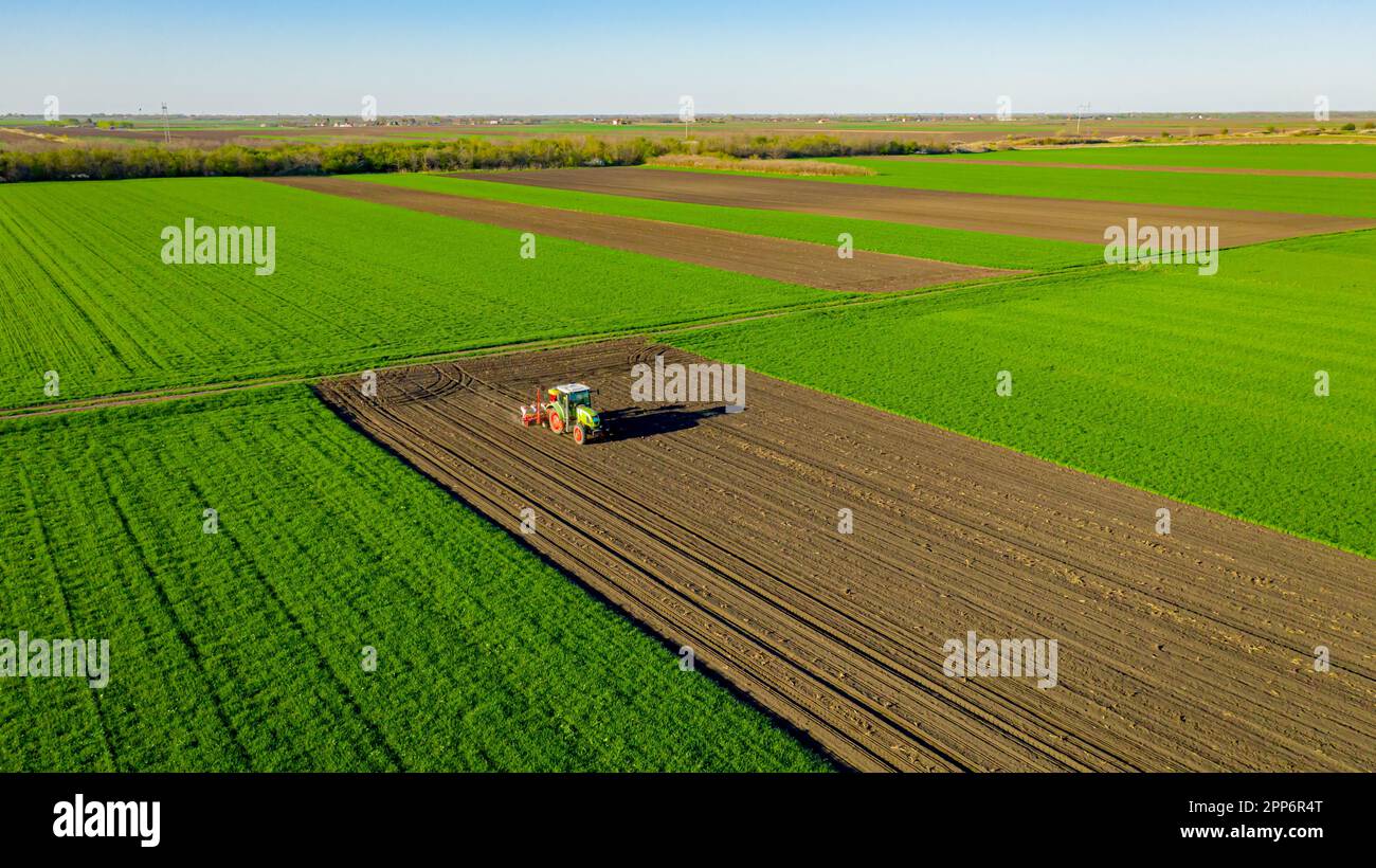 Above view, of tractor as pulling mechanical seeder machine over arable ...
