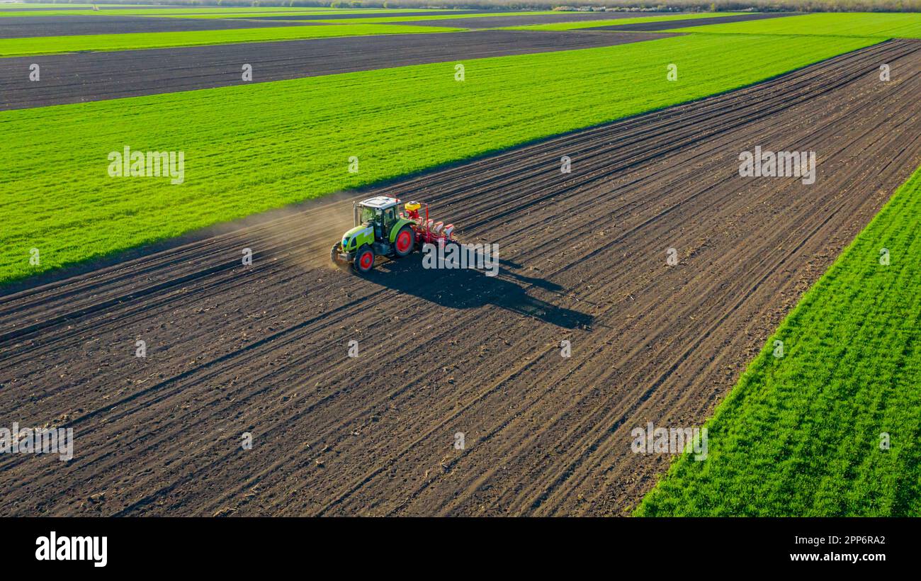 Above view, of tractor as pulling mechanical seeder machine over arable ...