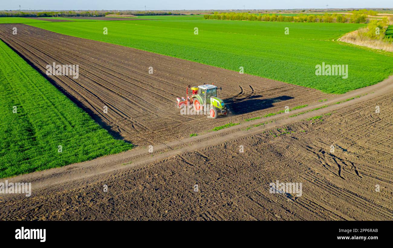 Above view, of tractor as pulling mechanical seeder machine over arable ...