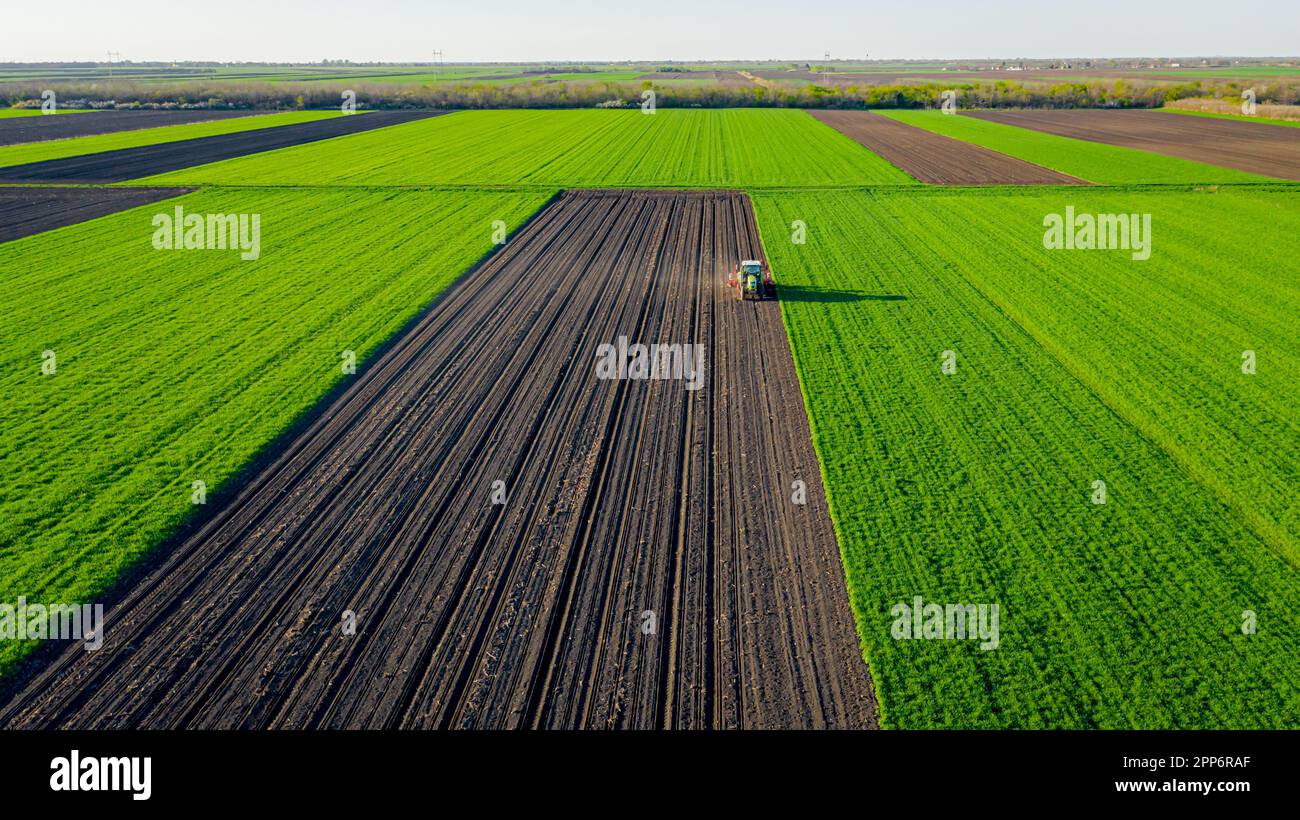 Above view, of tractor as pulling mechanical seeder machine over arable ...