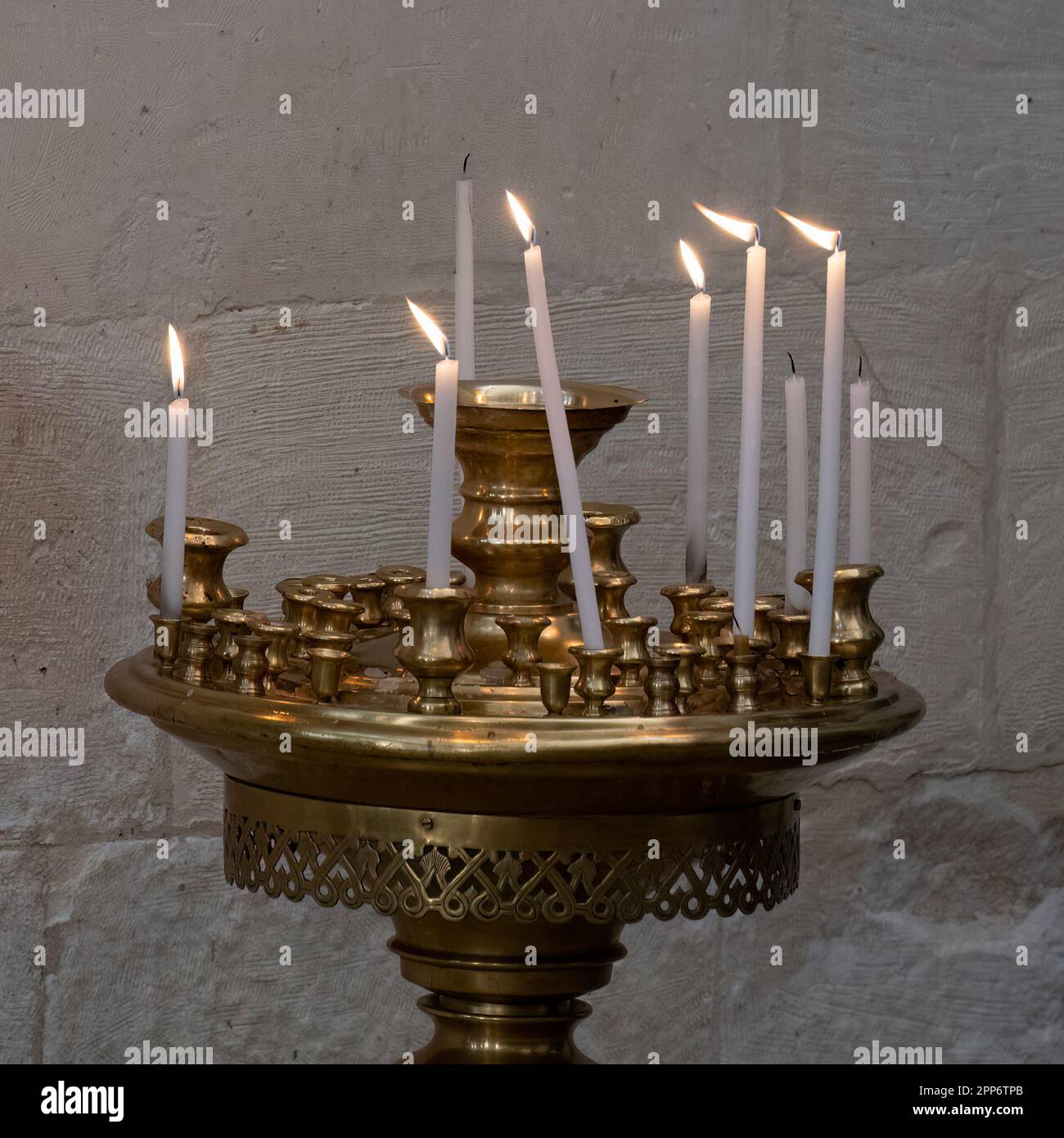 Multiple prayer candles in a brass stand in church, most of them ...