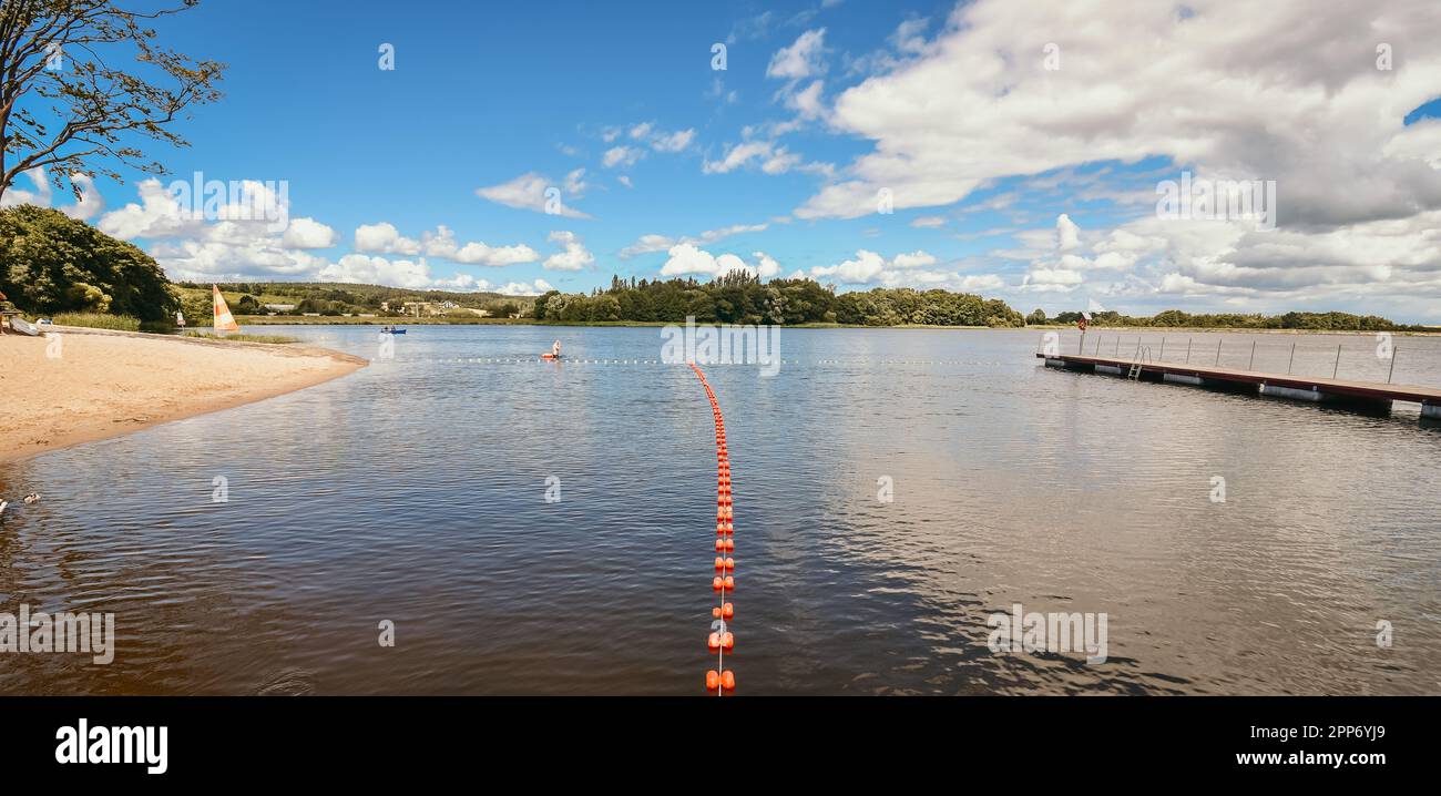 Wide view of small lake with sandy beach Stock Photo - Alamy