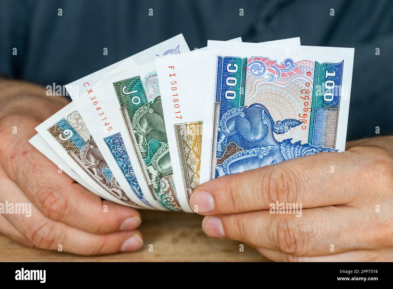 The man behind the desk has a bundle of Burmese money in his hand Stock ...